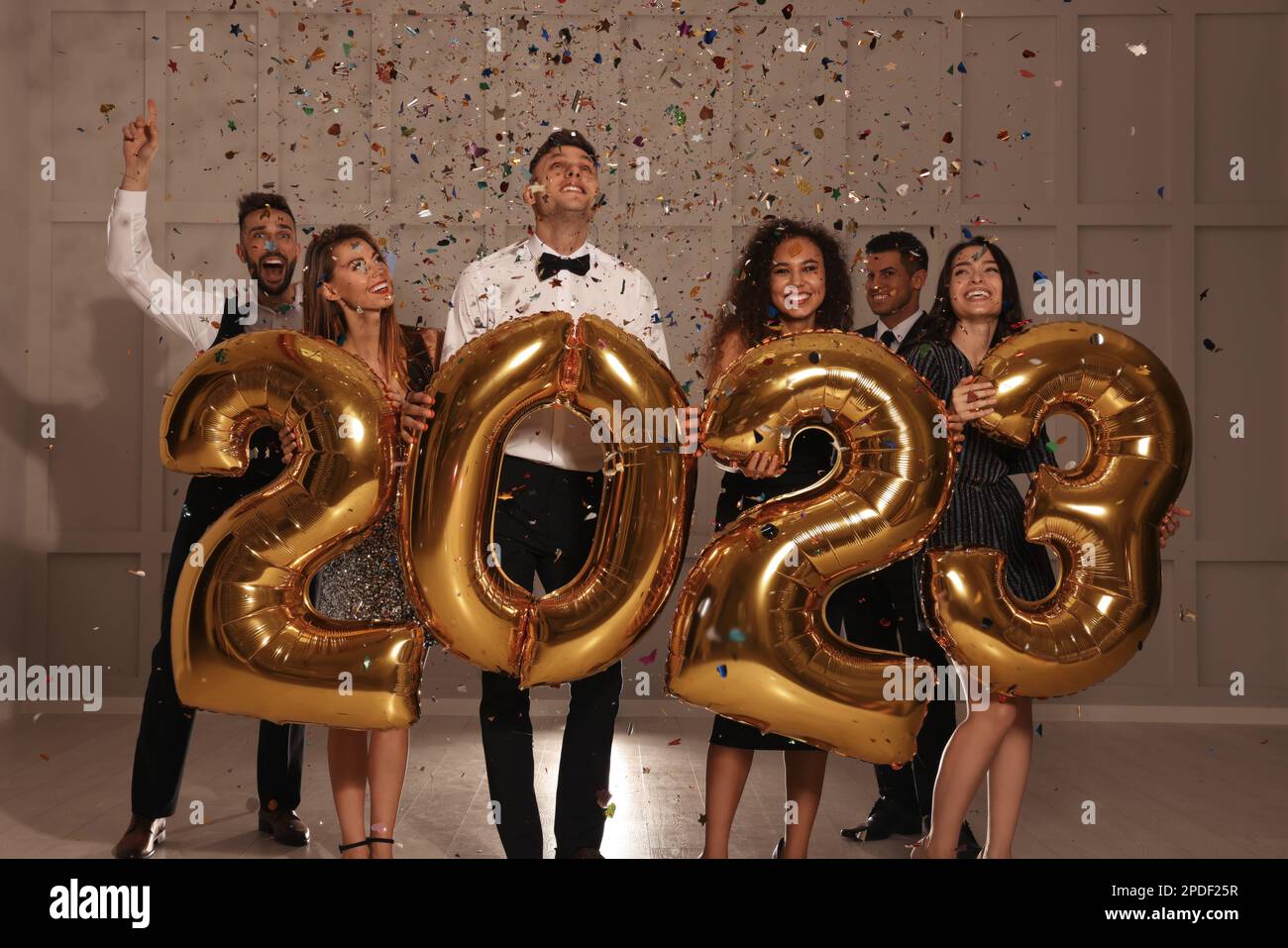 Happy friends with golden 2023 balloons indoors. New Year celebration ...