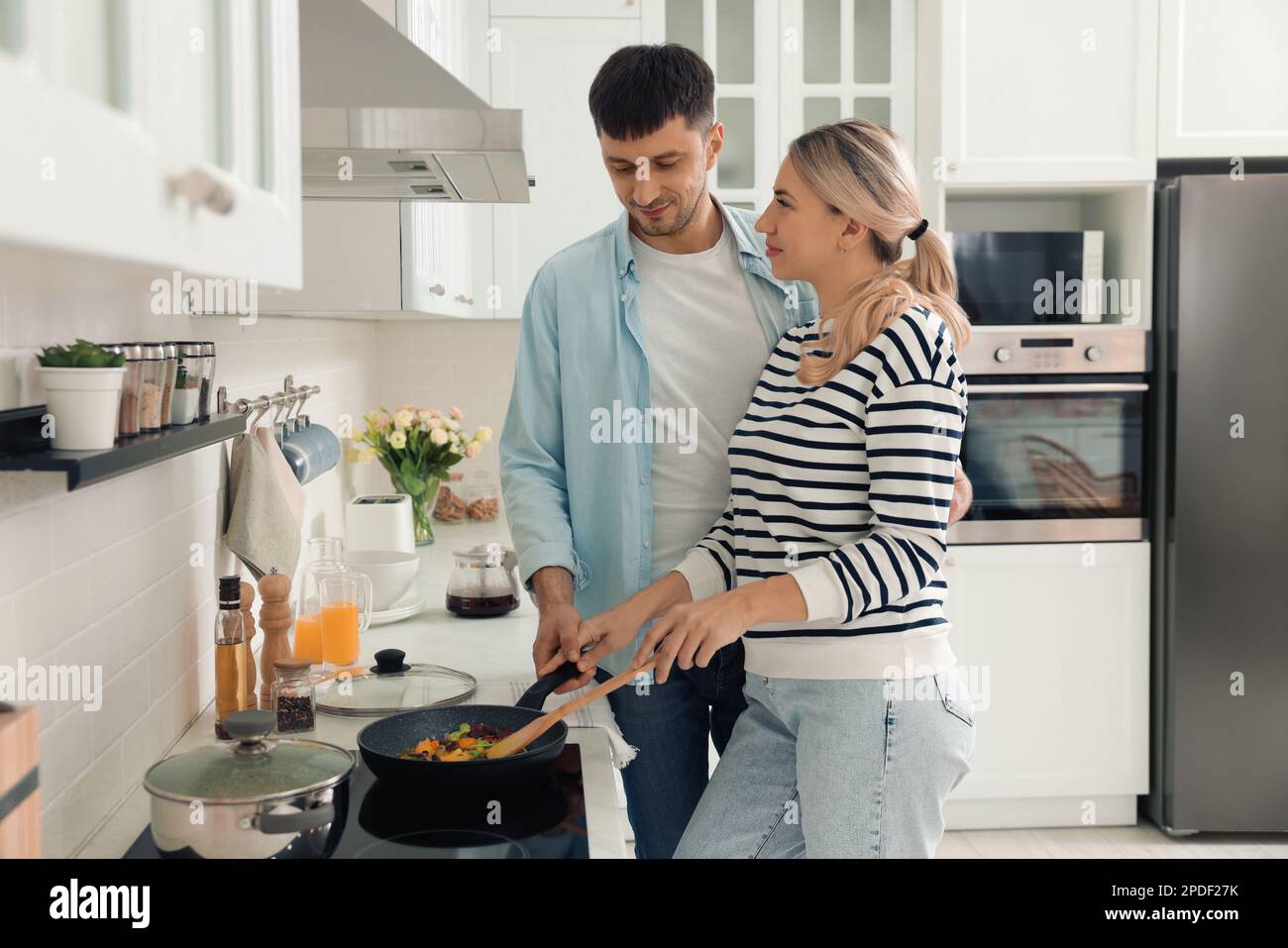 Happy couple cooking breakfast together in kitchen Stock Photo - Alamy