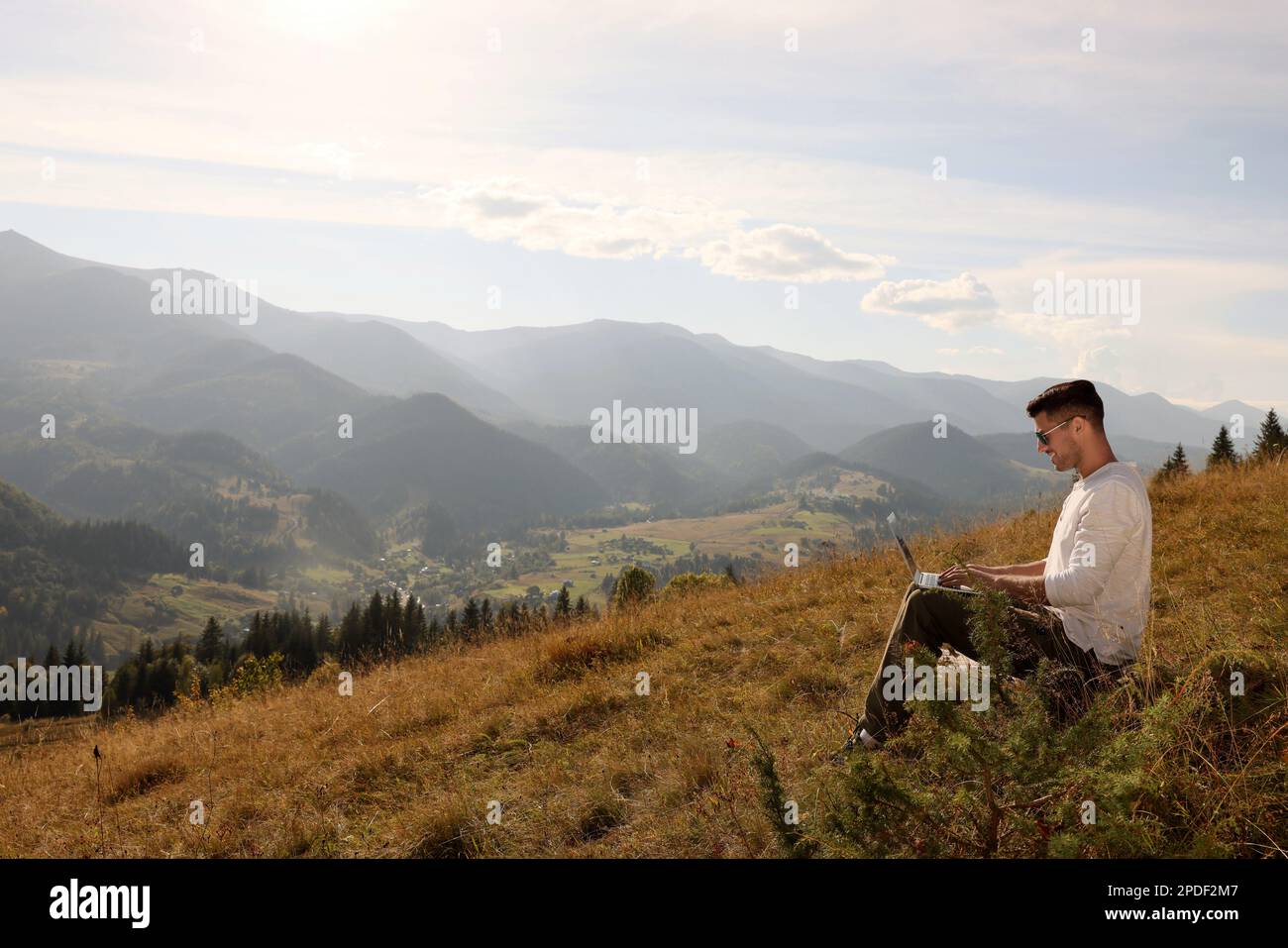 Man working with laptop outdoors surrounded by beautiful nature. Space ...