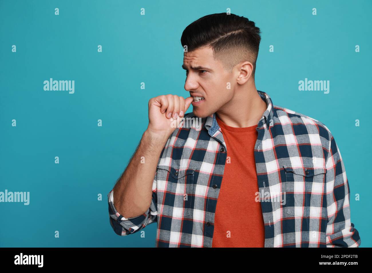 Man biting his nails on light blue background, space for text. Bad ...