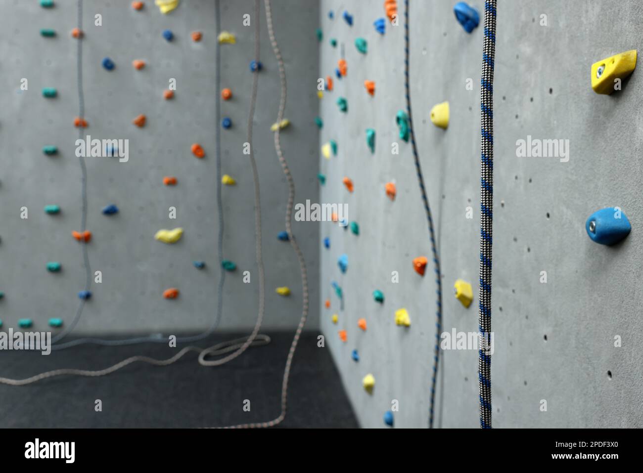 Climbing wall with holds and ropes in gym. Extreme sport Stock Photo ...