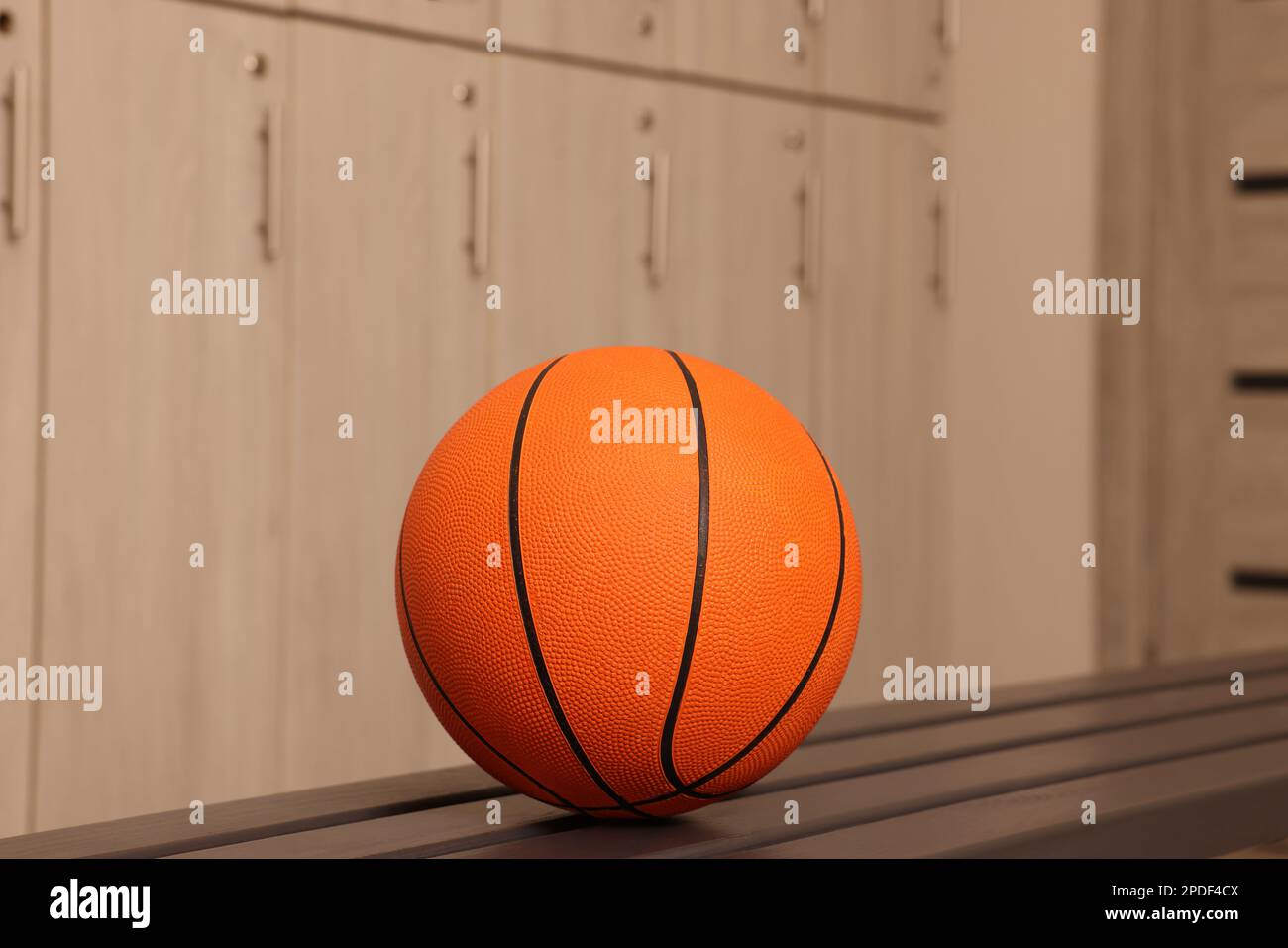 Orange basketball ball on wooden bench in locker room Stock Photo - Alamy