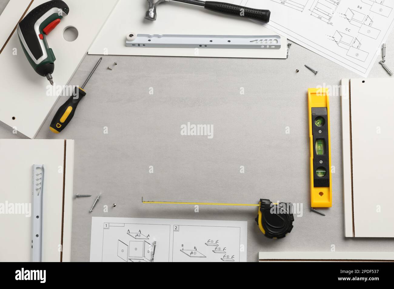 Frame of furniture assembly parts and tools on light grey background ...