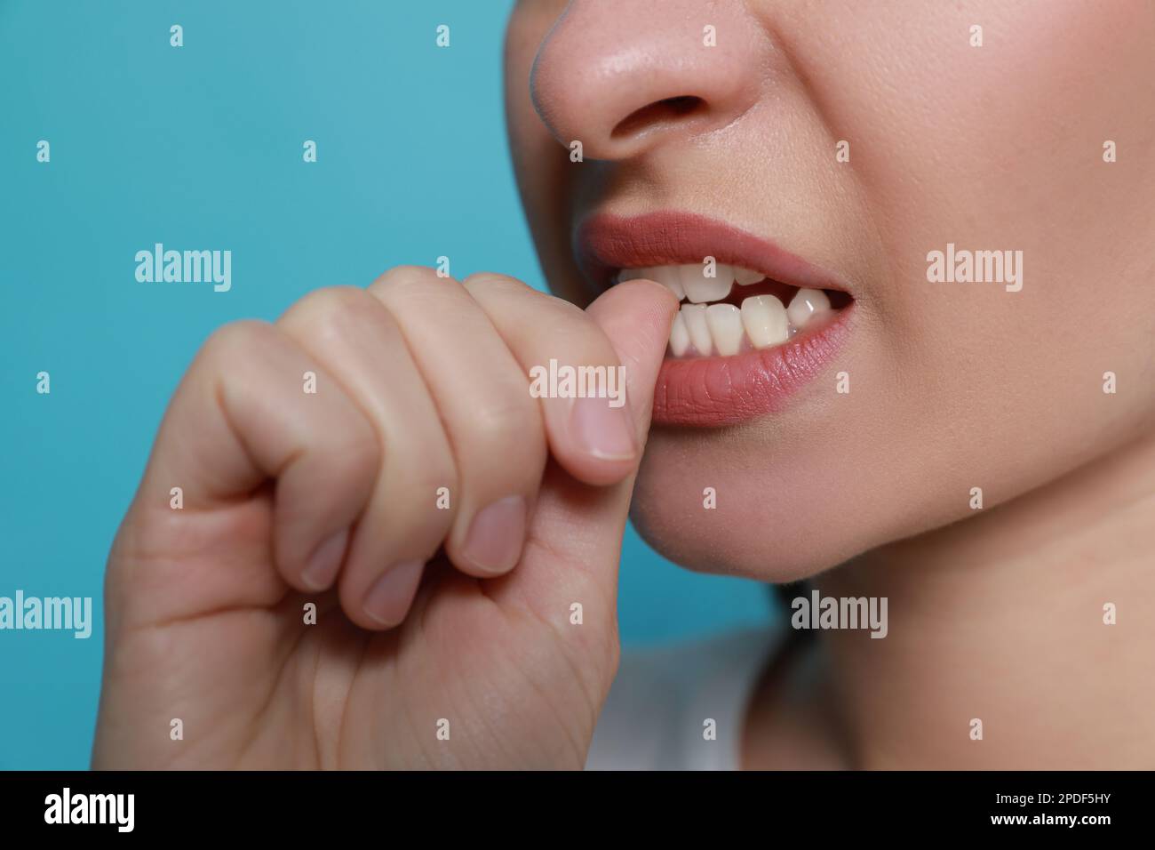 Young woman biting her nails on light blue background, closeup Stock ...