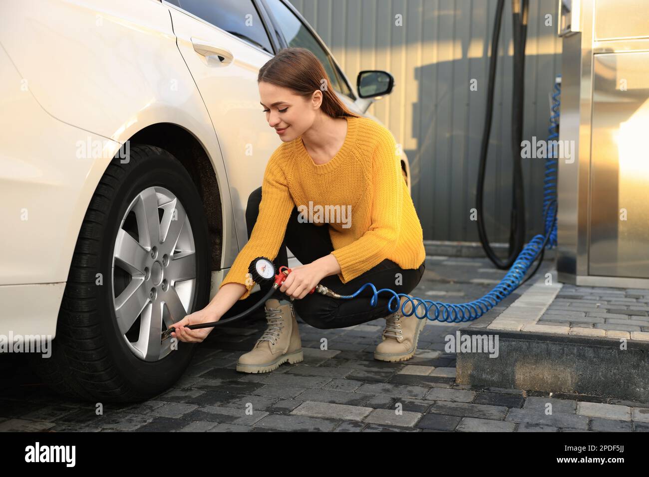 Young woman inflating tire at car service Stock Photo - Alamy