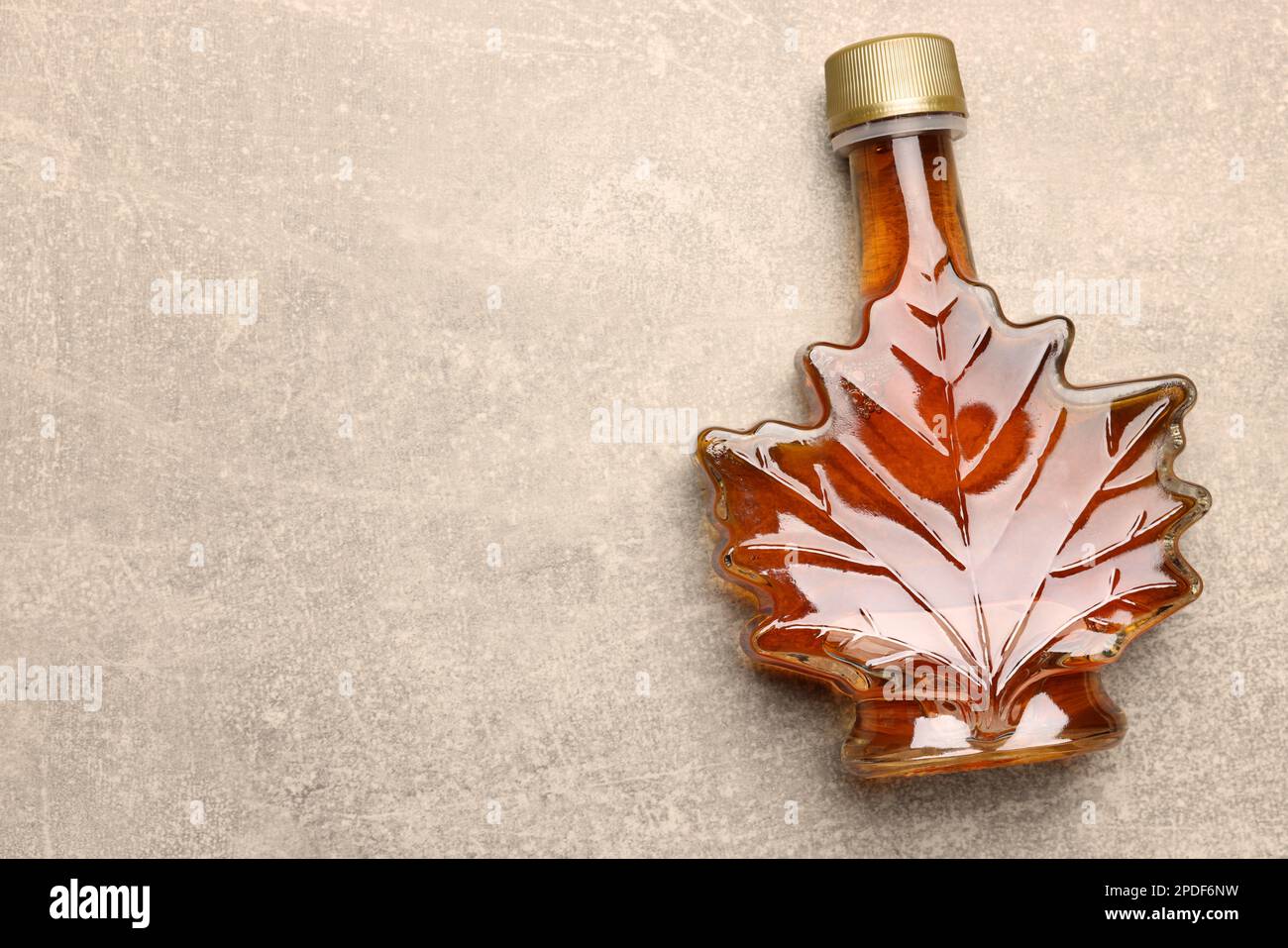 Leaf shaped bottle of tasty maple syrup on light grey table, top view. Space for text Stock ...