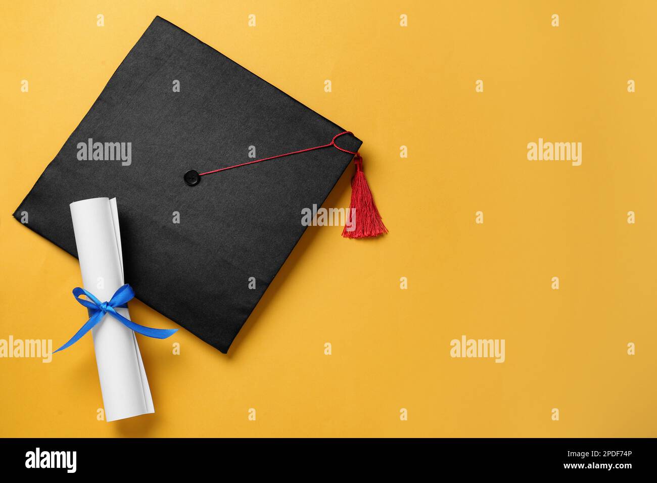 Graduation hat and diploma on yellow background, flat lay. Space for ...