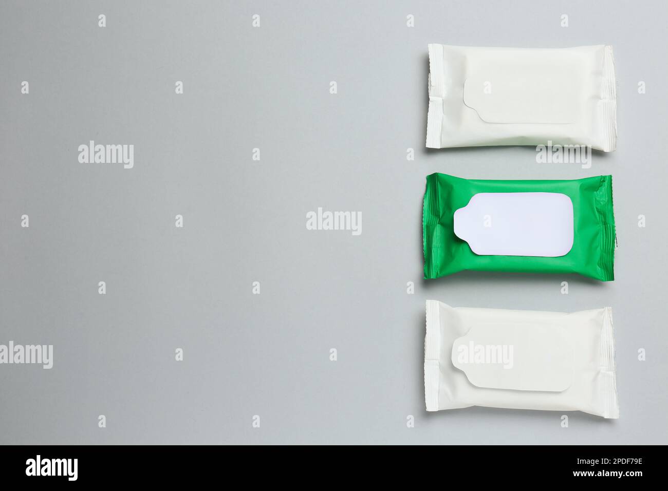 Wet wipes flow packs on light grey background, flat lay. Space for text ...
