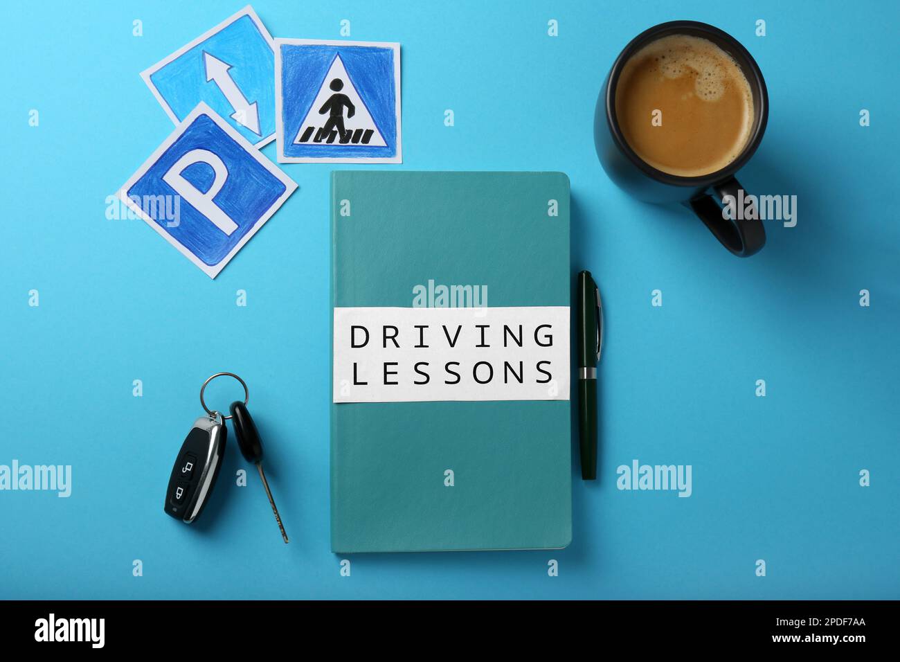 Flat lay composition with workbook for driving lessons on light blue ...