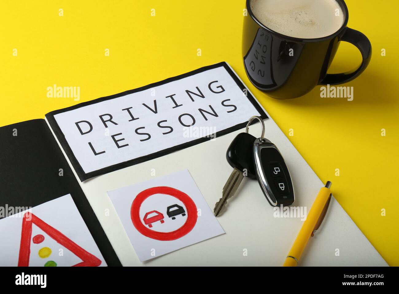 Workbook for driving lessons, cup of coffee and keys on yellow ...