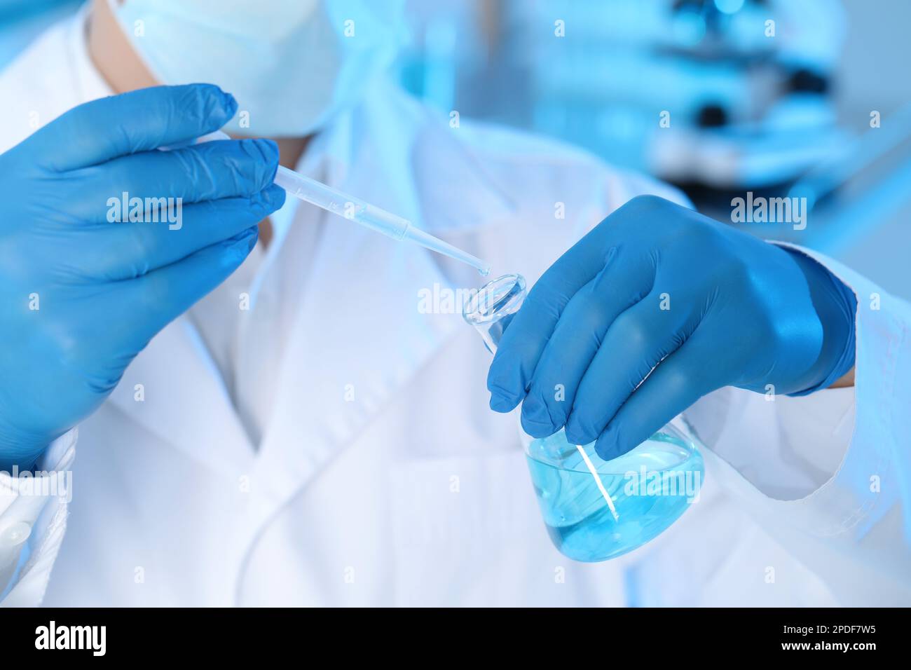 Scientist dripping sample into flask in laboratory, closeup. Medical ...