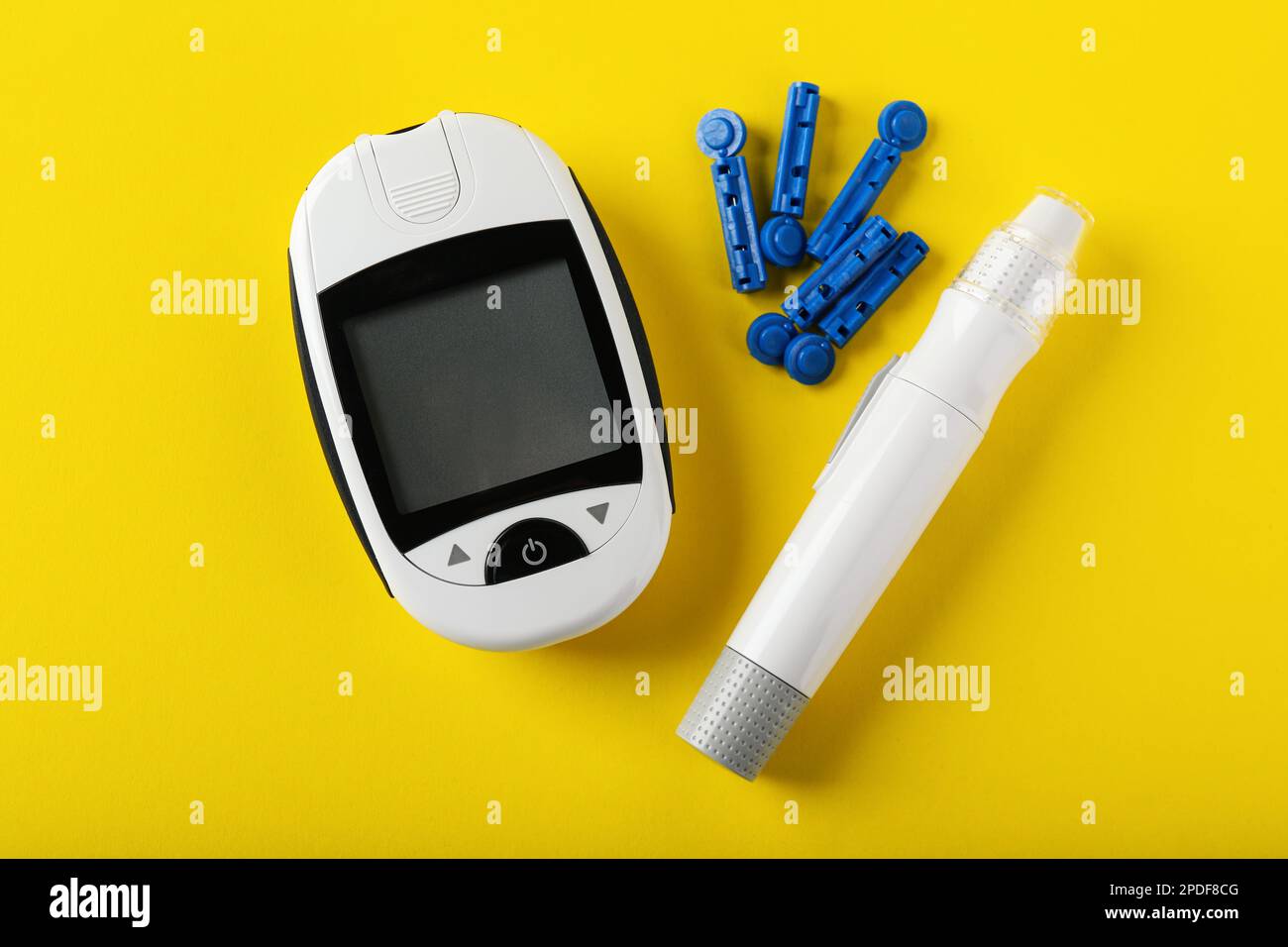 Digital glucometer, lancets and pen on yellow background, flat lay ...