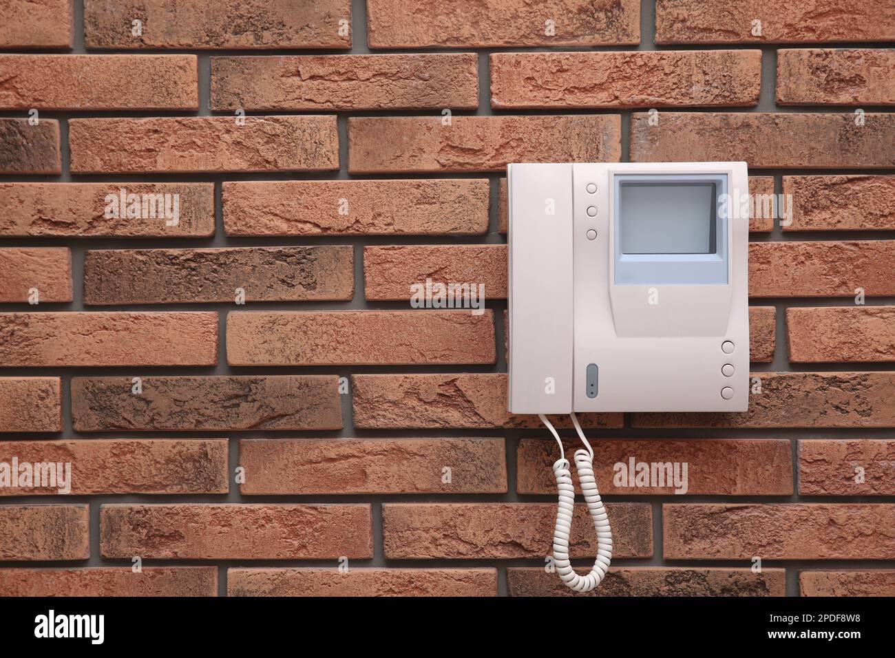 Modern intercom system with handset on red brick wall, space for text ...