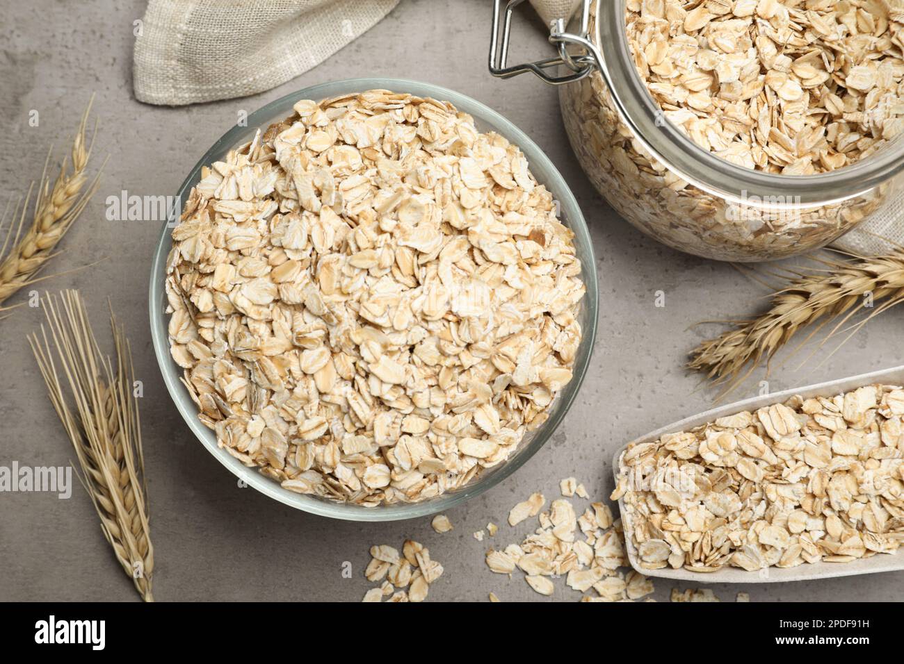 Oatmeal, glass bowl, jar and scoop on grey table, flat lay Stock Photo ...
