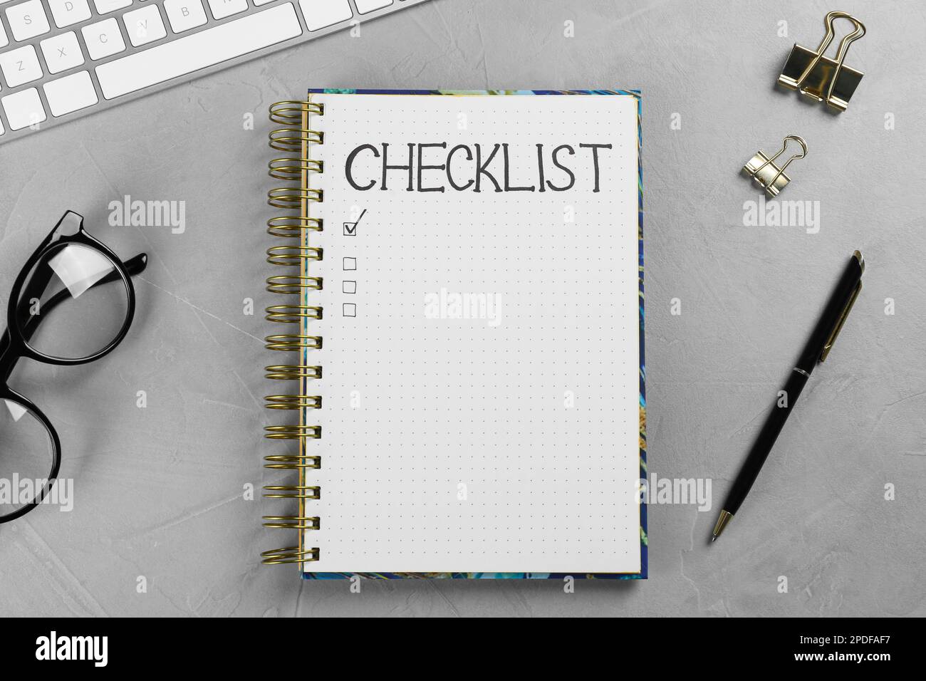 Notebook with inscription Checklist, computer keyboard, eyeglasses and ...
