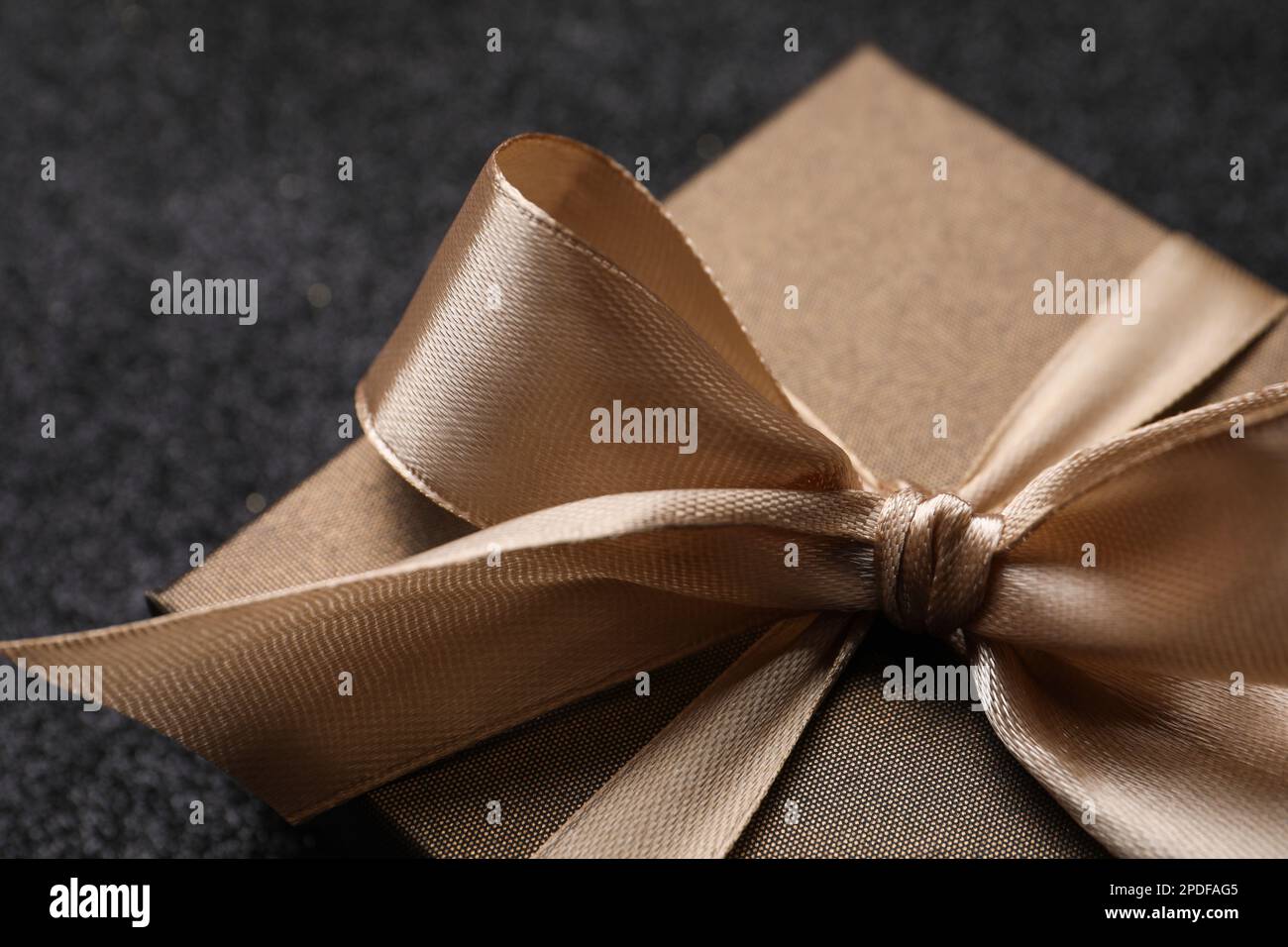 Shiny gift box with golden bow on black background, closeup Stock Photo ...