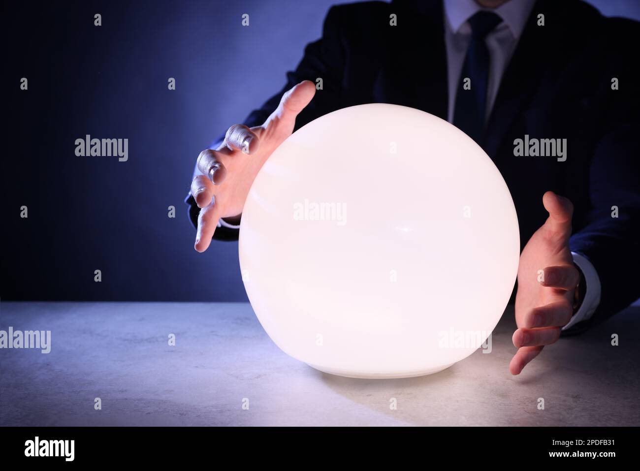 Businessman using glowing crystal ball to predict future at table ...