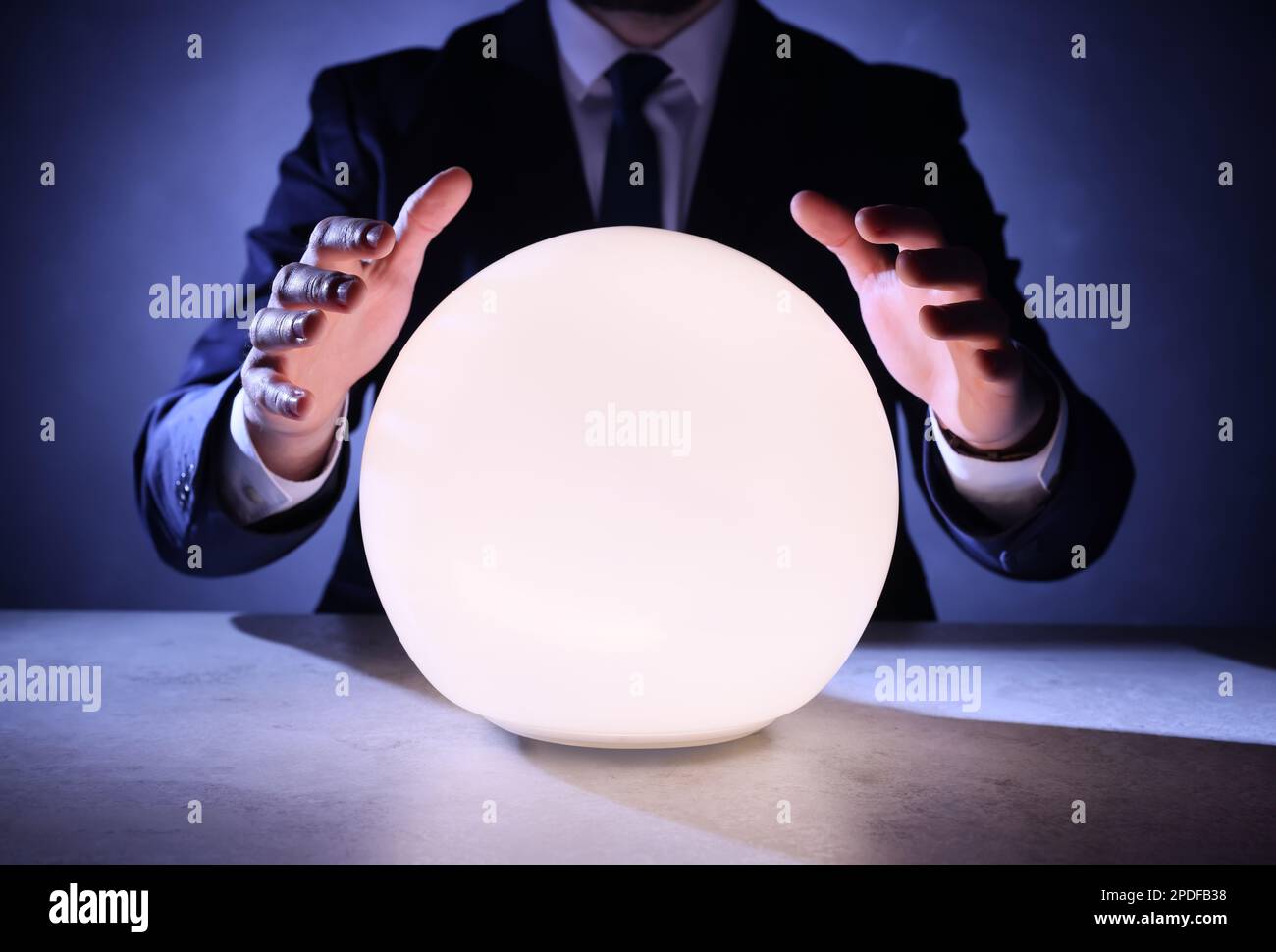Businessman using glowing crystal ball to predict future at table ...