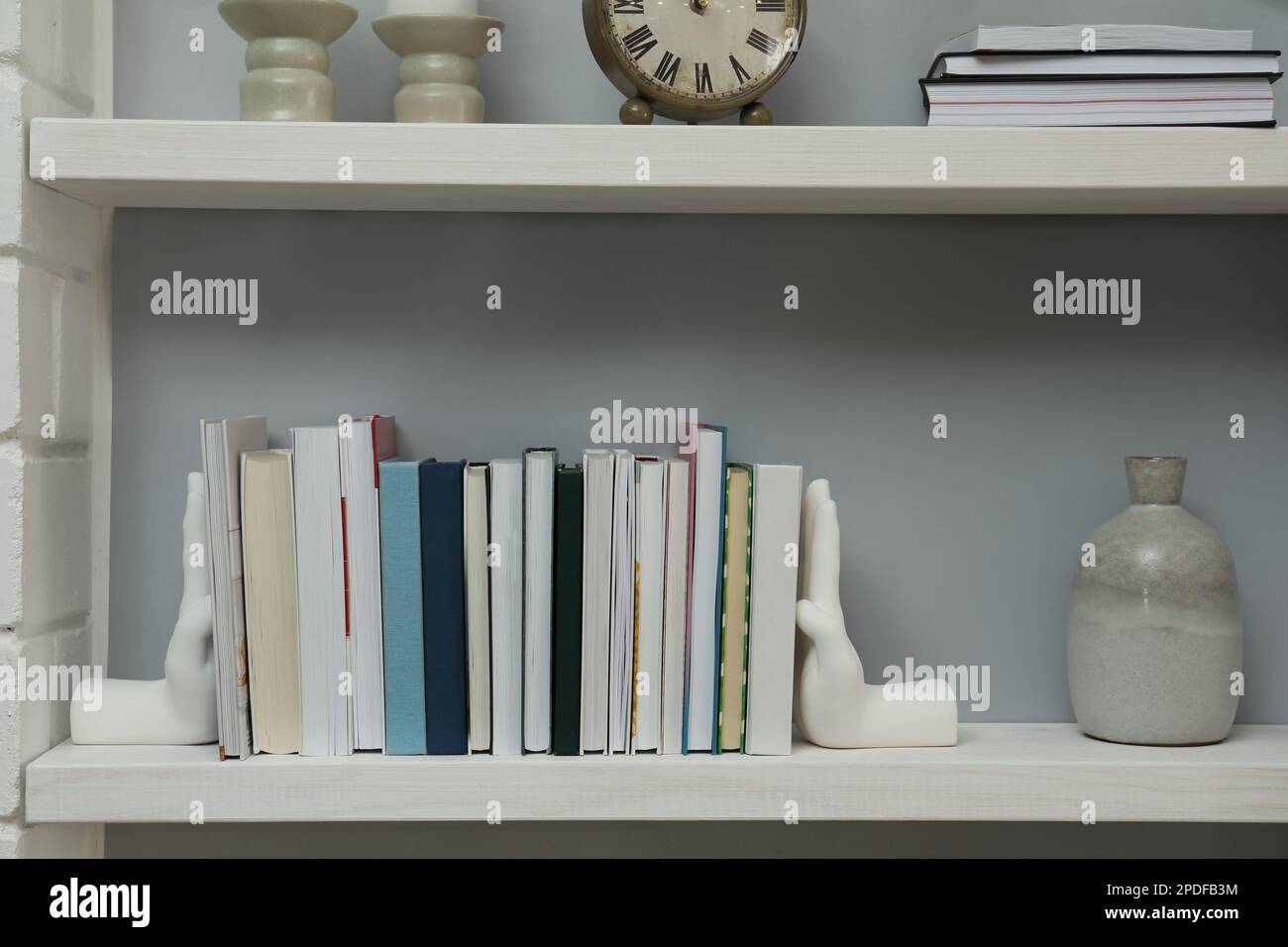Hand shaped bookends with books on shelf indoors. Interior design Stock ...