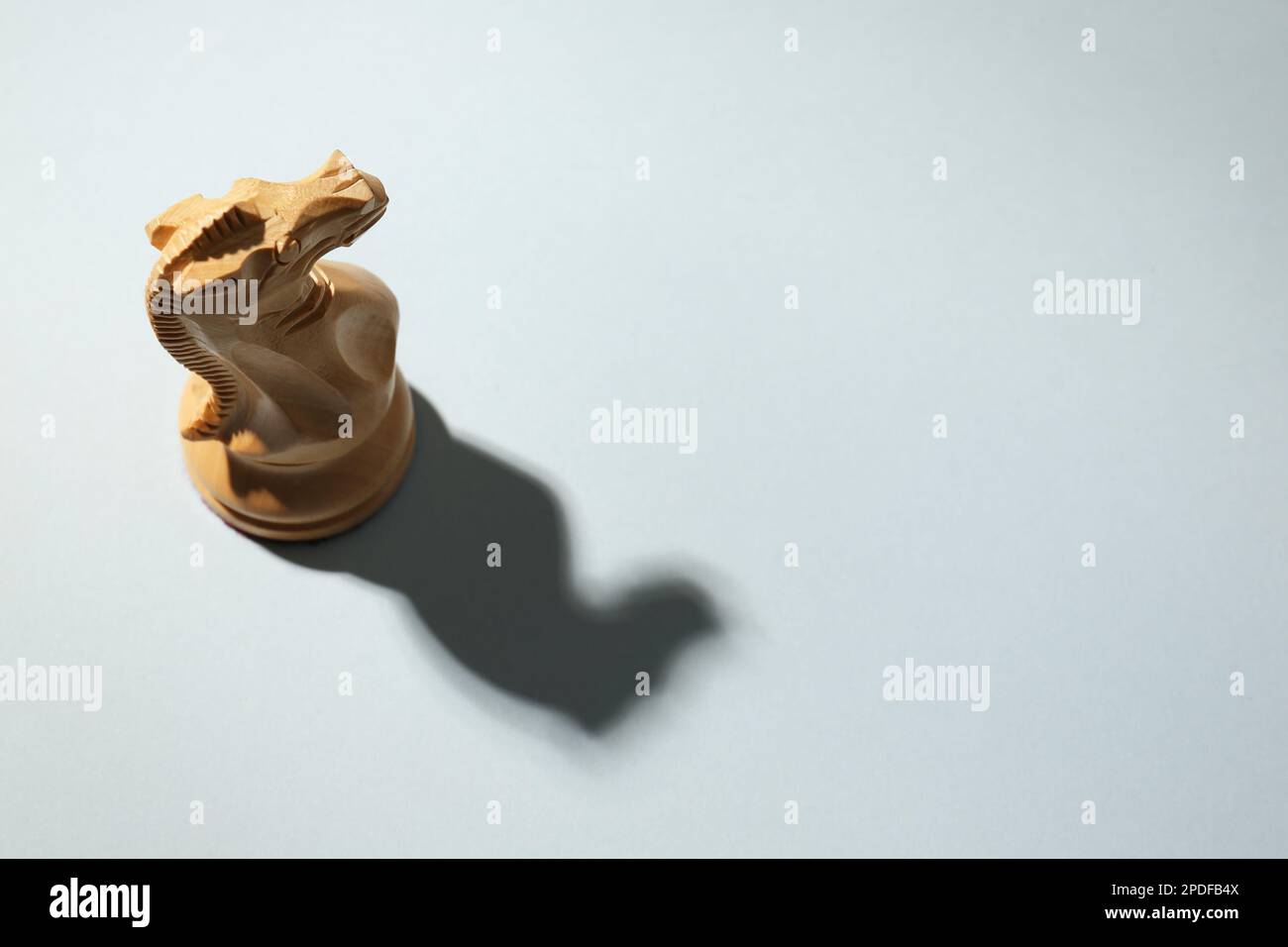White wooden chess knight on light grey background, above view. Space ...