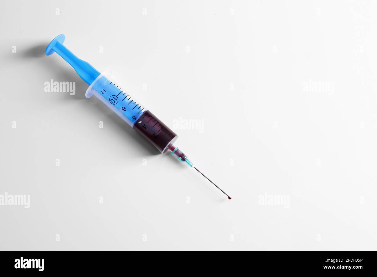Plastic syringe with blood on white background Stock Photo - Alamy