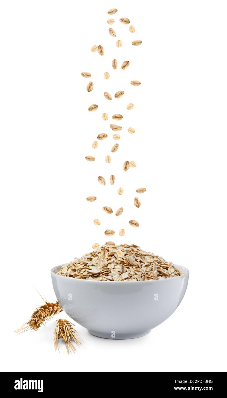 Dry uncooked oatmeal falling into bowl on white background Stock Photo ...