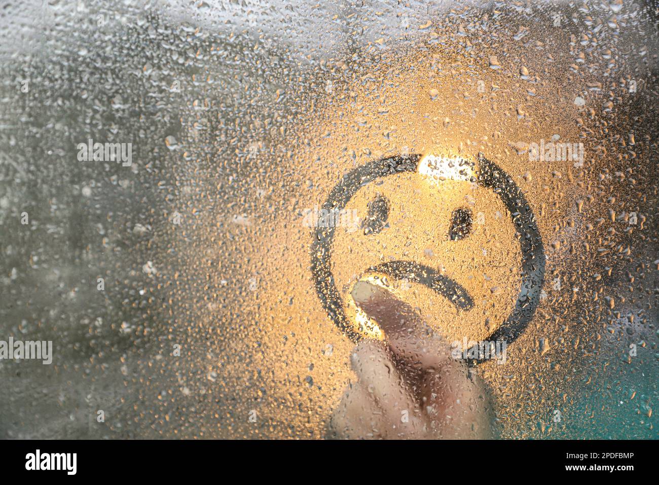 Woman drawing sad face on foggy window at rainy weather Stock Photo - Alamy