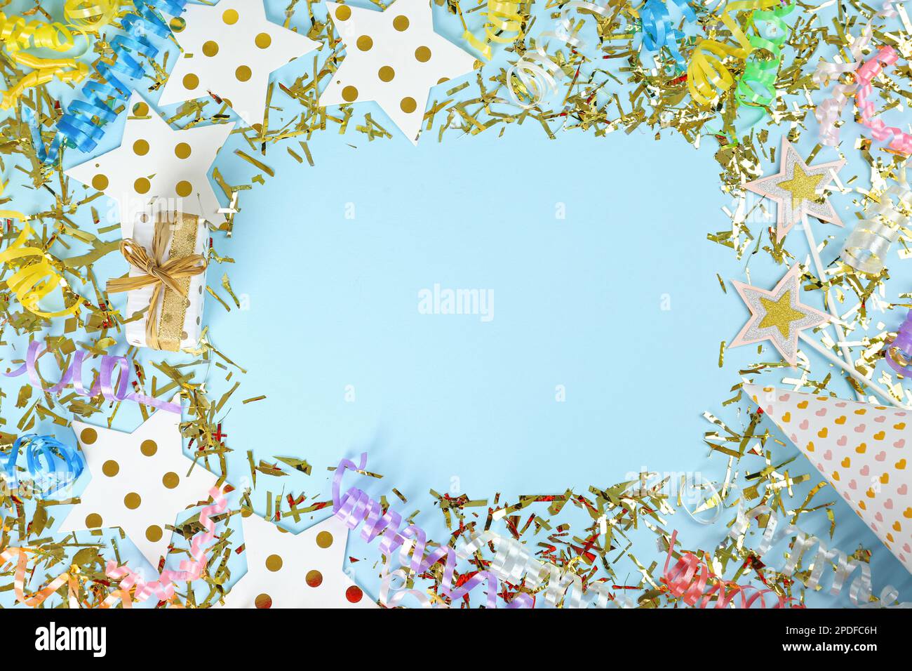 Frame of serpentine streamers and other party accessories on light blue ...