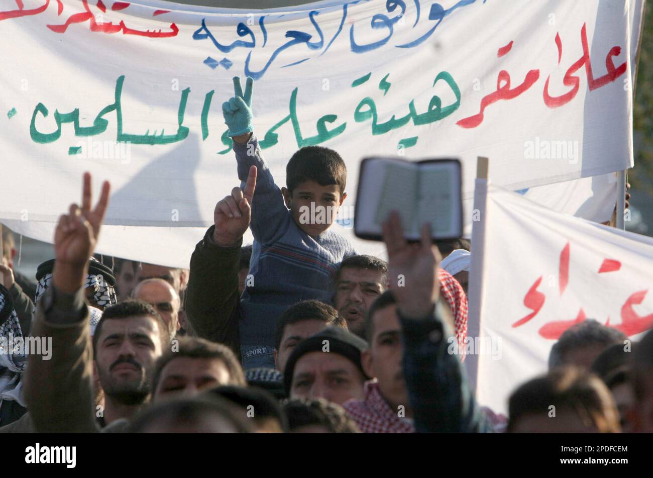Sunni Muslims hold banners denouncing the Sunday raid on the Um al-Qura ...