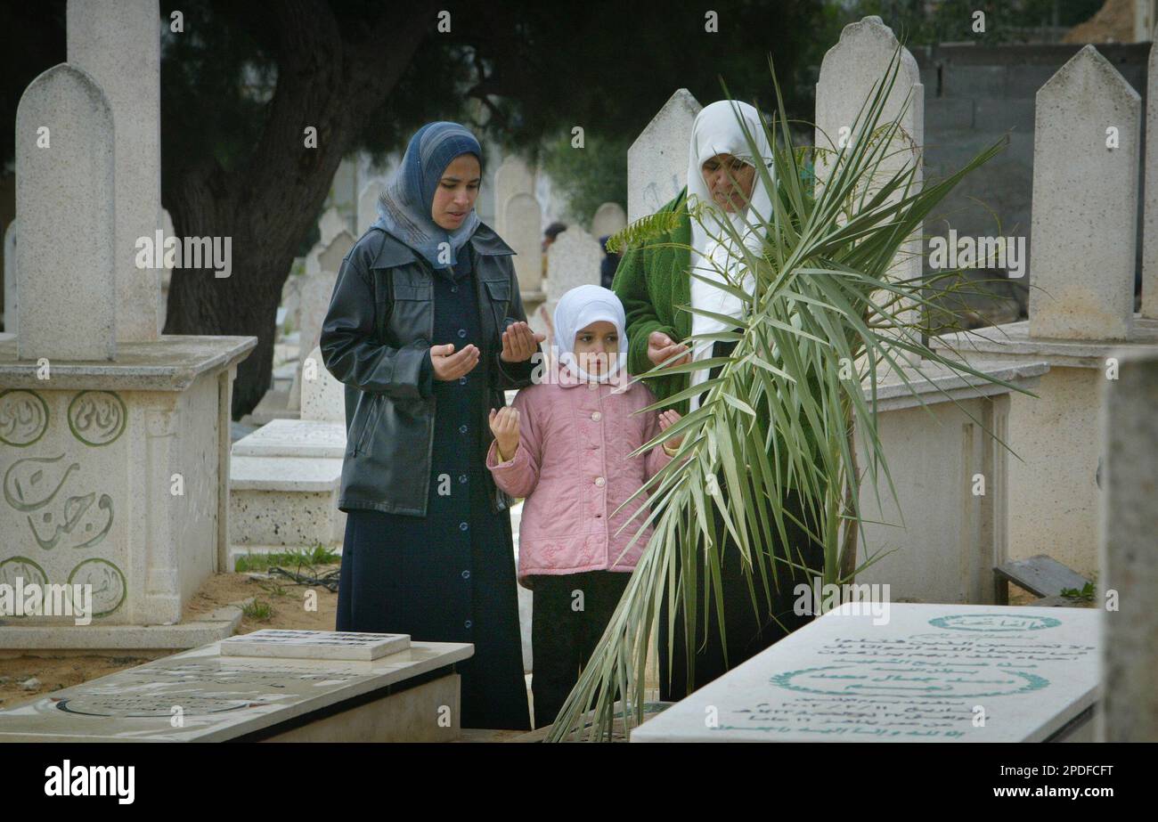 A Palestinian family prays over the grave of late Hamas founder Sheik Ahmed Yassin, at the ...