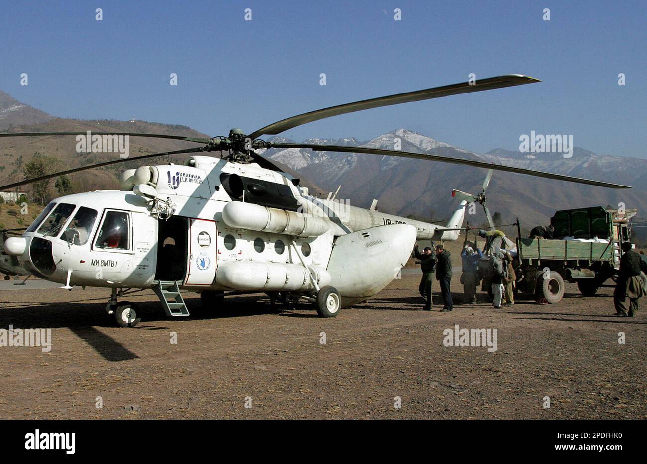 Laborers of World Food Program load the relief aid into a UN helicopter ...
