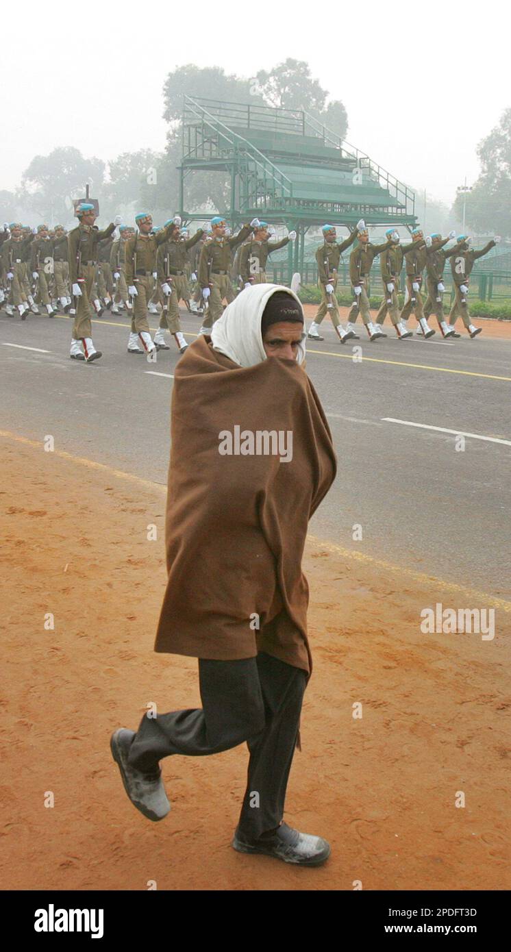A laborer walks past Indian Para-military force soldiers practicing for ...
