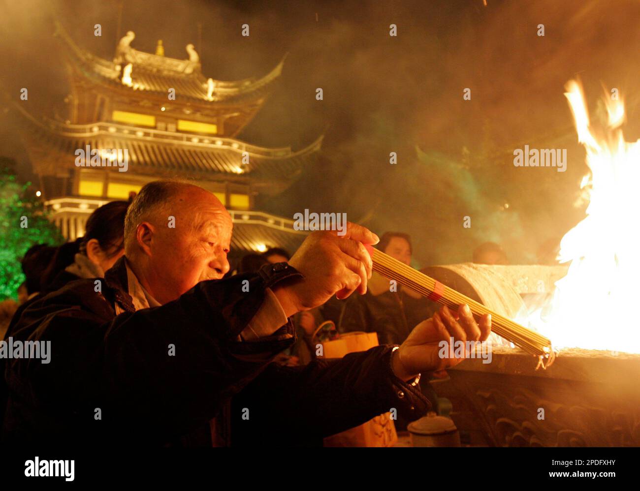 A Chinese man burns a joss stick as he celebrates the start of the new ...