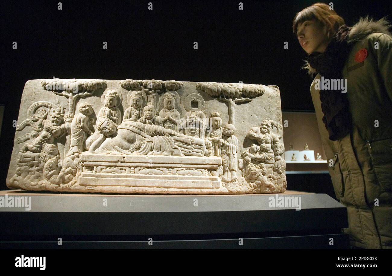 A Chinese woman looks inside stone box previously used to house the ...