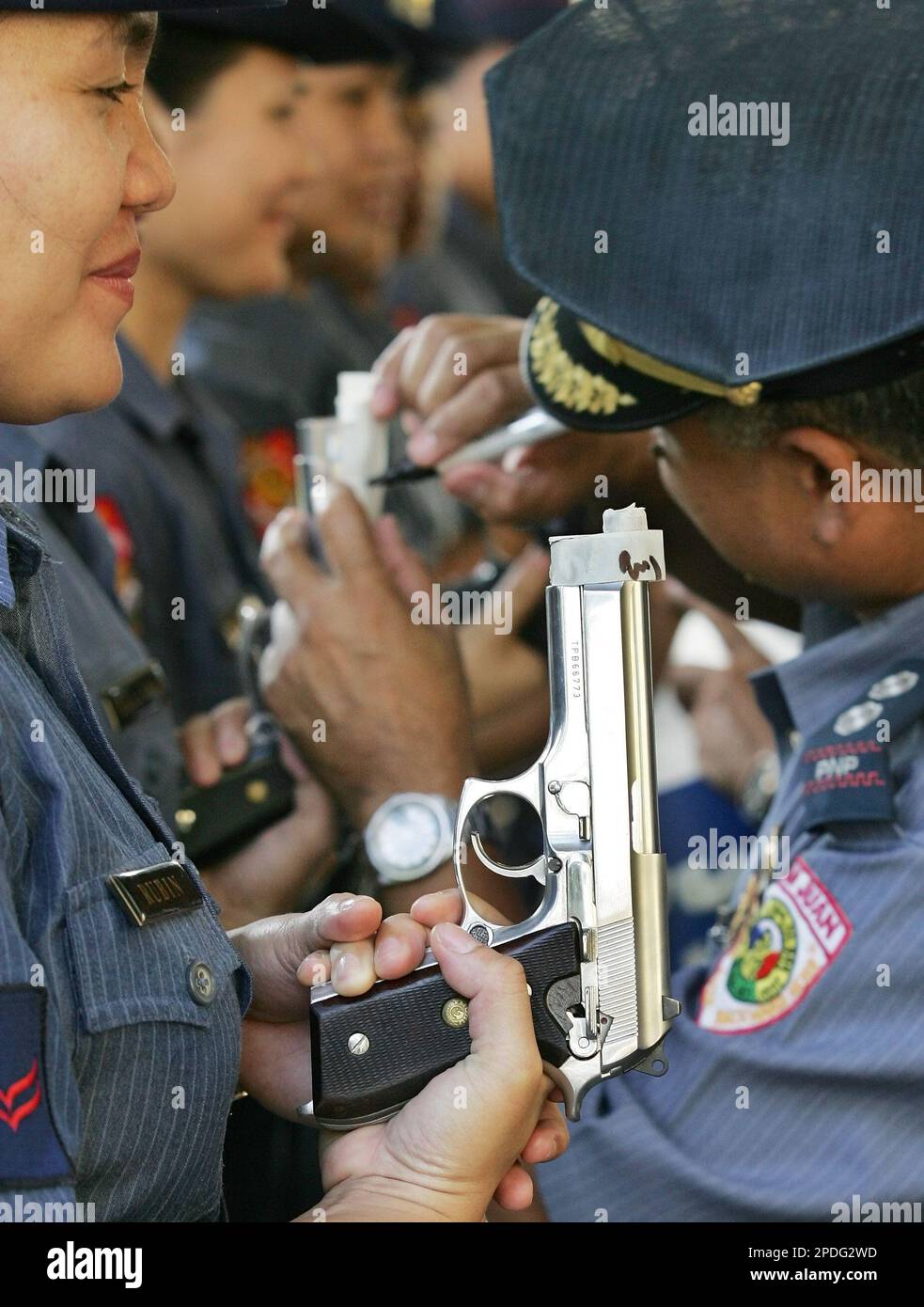 A policewoman displays her taped pistol as Philippine police ...