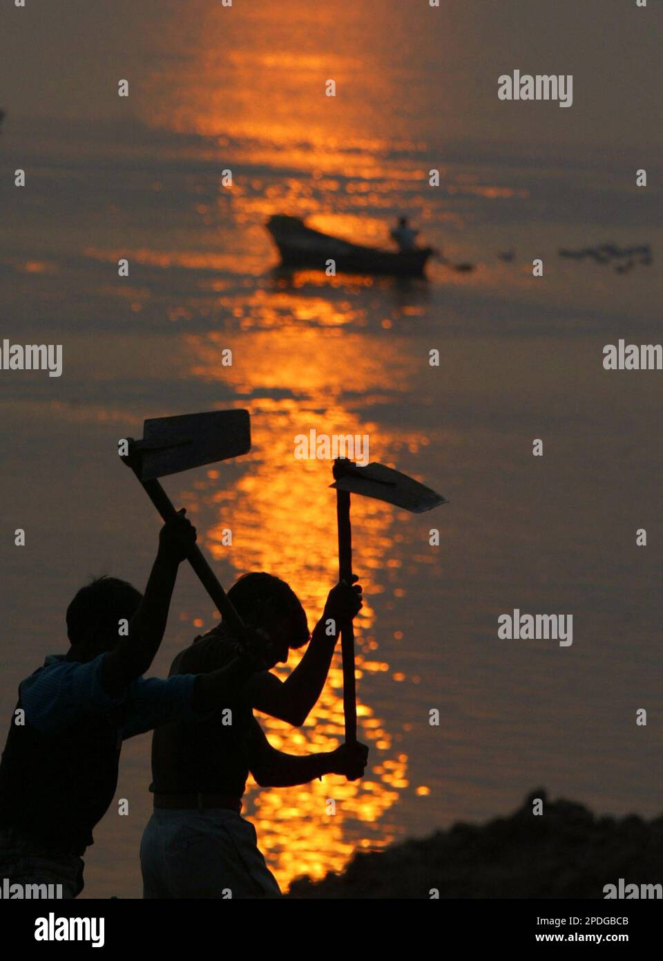 Indian laborers work on the banks of the River Ganges at sunset in ...