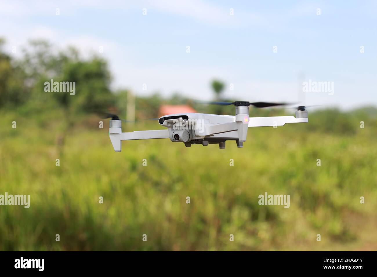 a photo of a drone flying with a blurry propeller against a green open ...