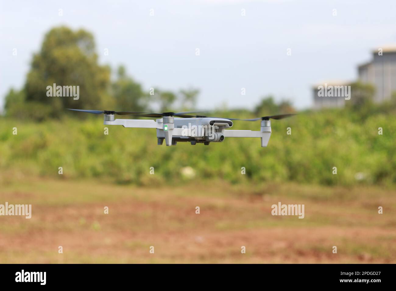 a photo of a drone flying with a blurry propeller against a green open ...