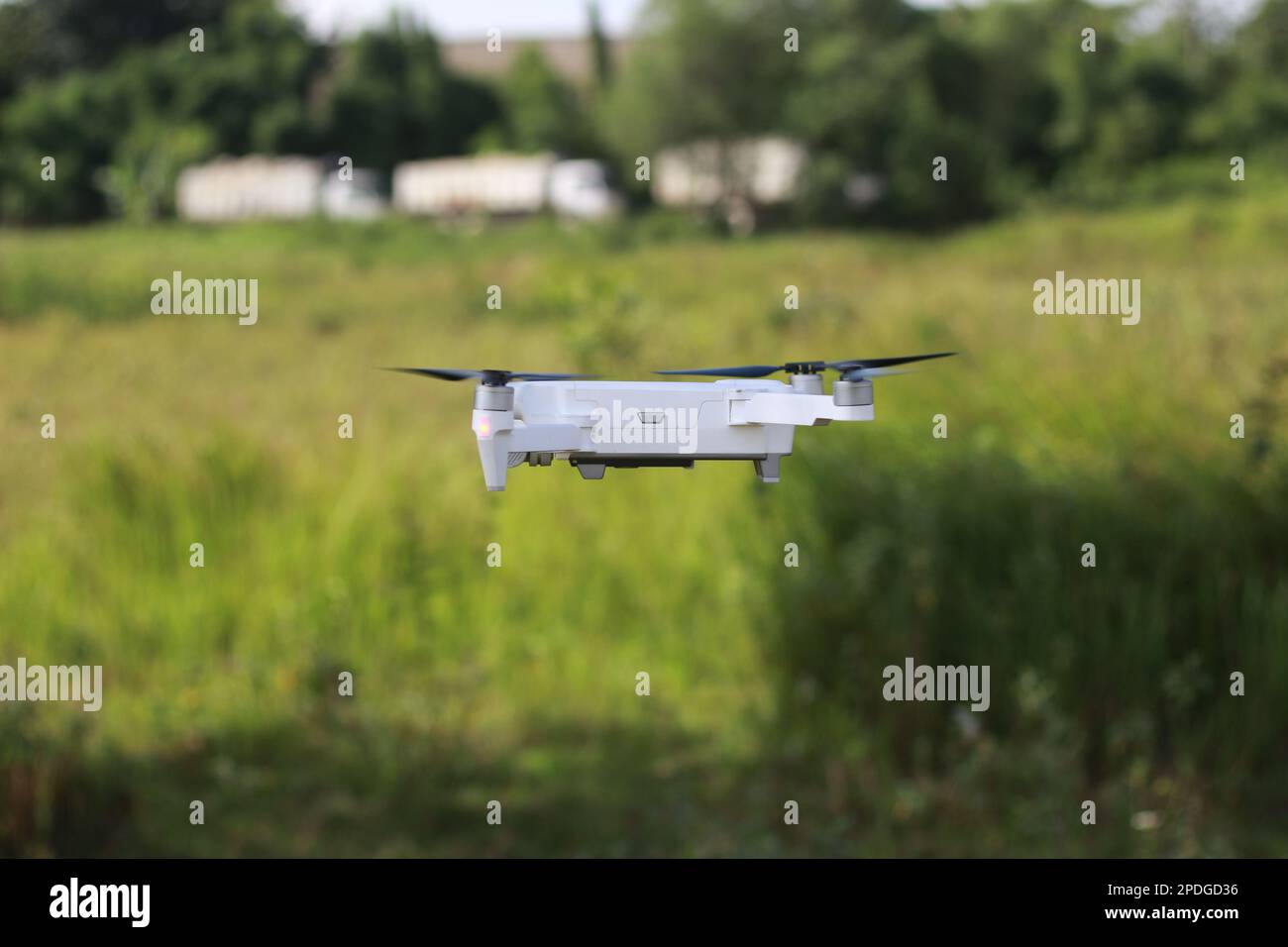 a photo of a drone flying with a blurry propeller against a green open ...