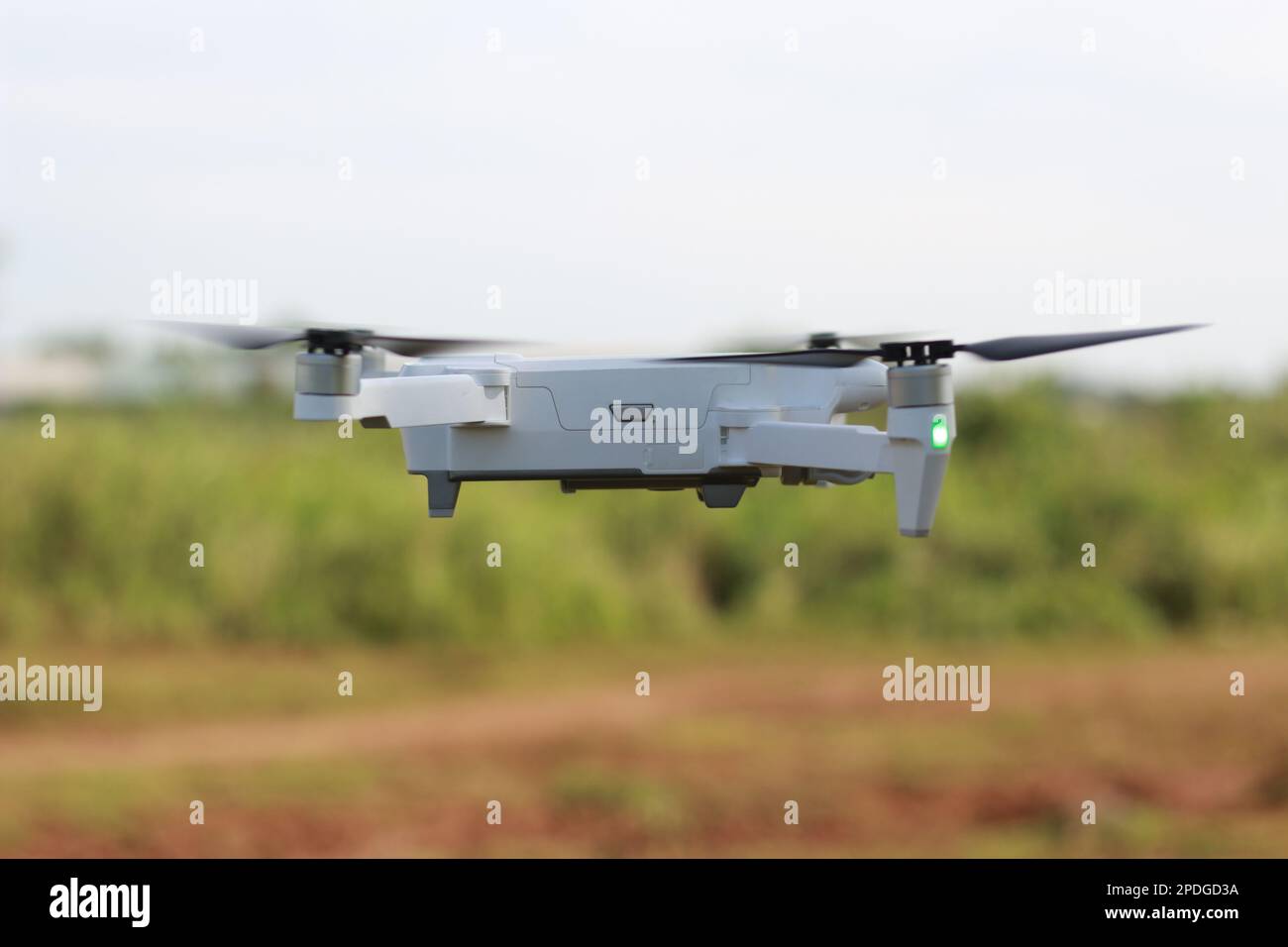 a photo of a drone flying with a blurry propeller against a green open ...