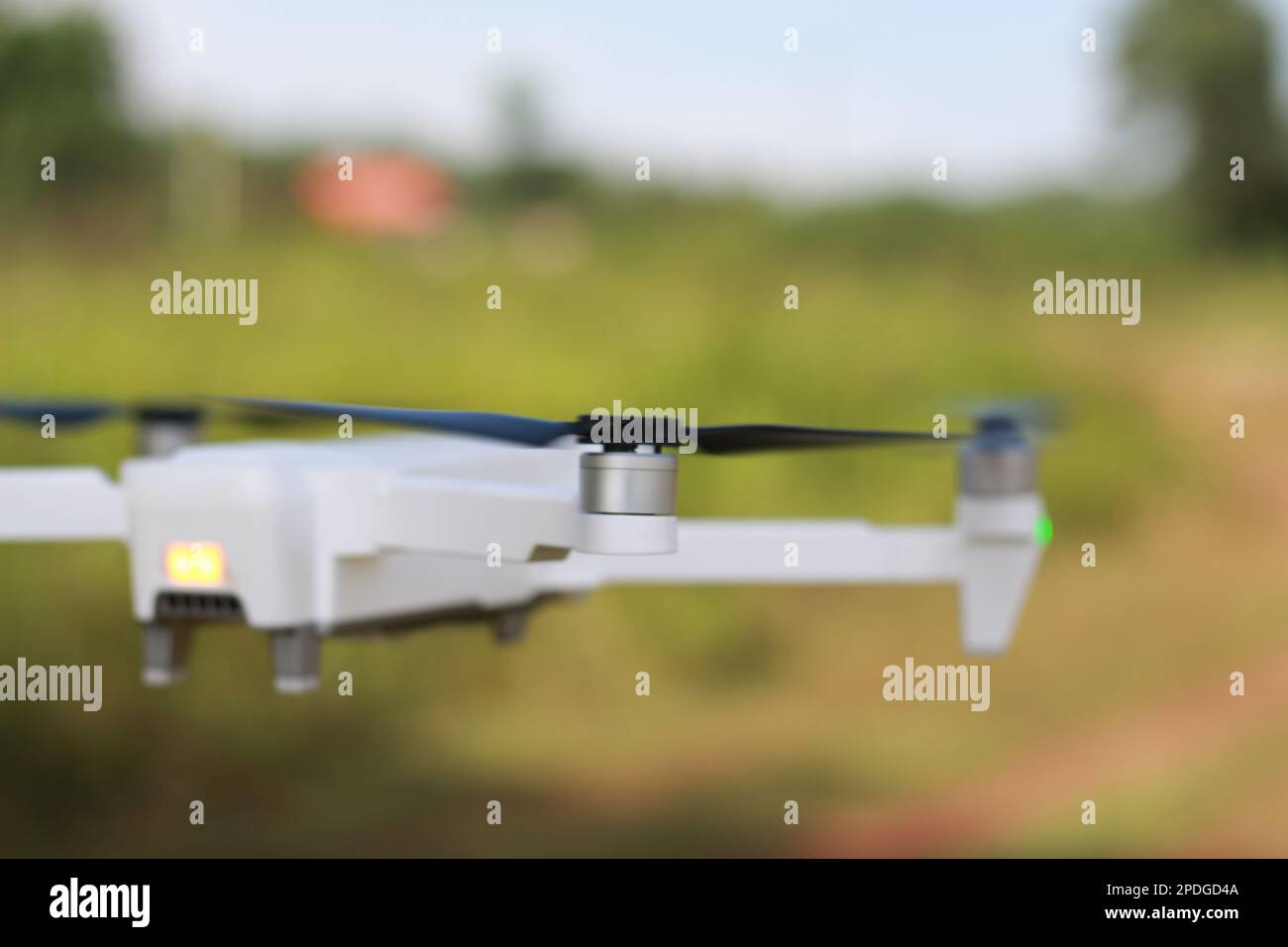 a photo of a drone flying with a blurry propeller against a green open ...