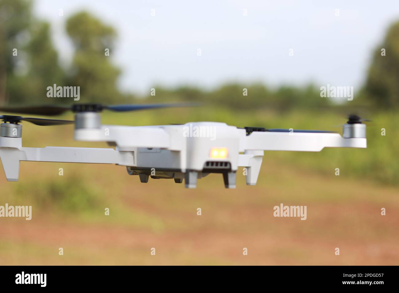a photo of a drone flying with a blurry propeller against a green open ...
