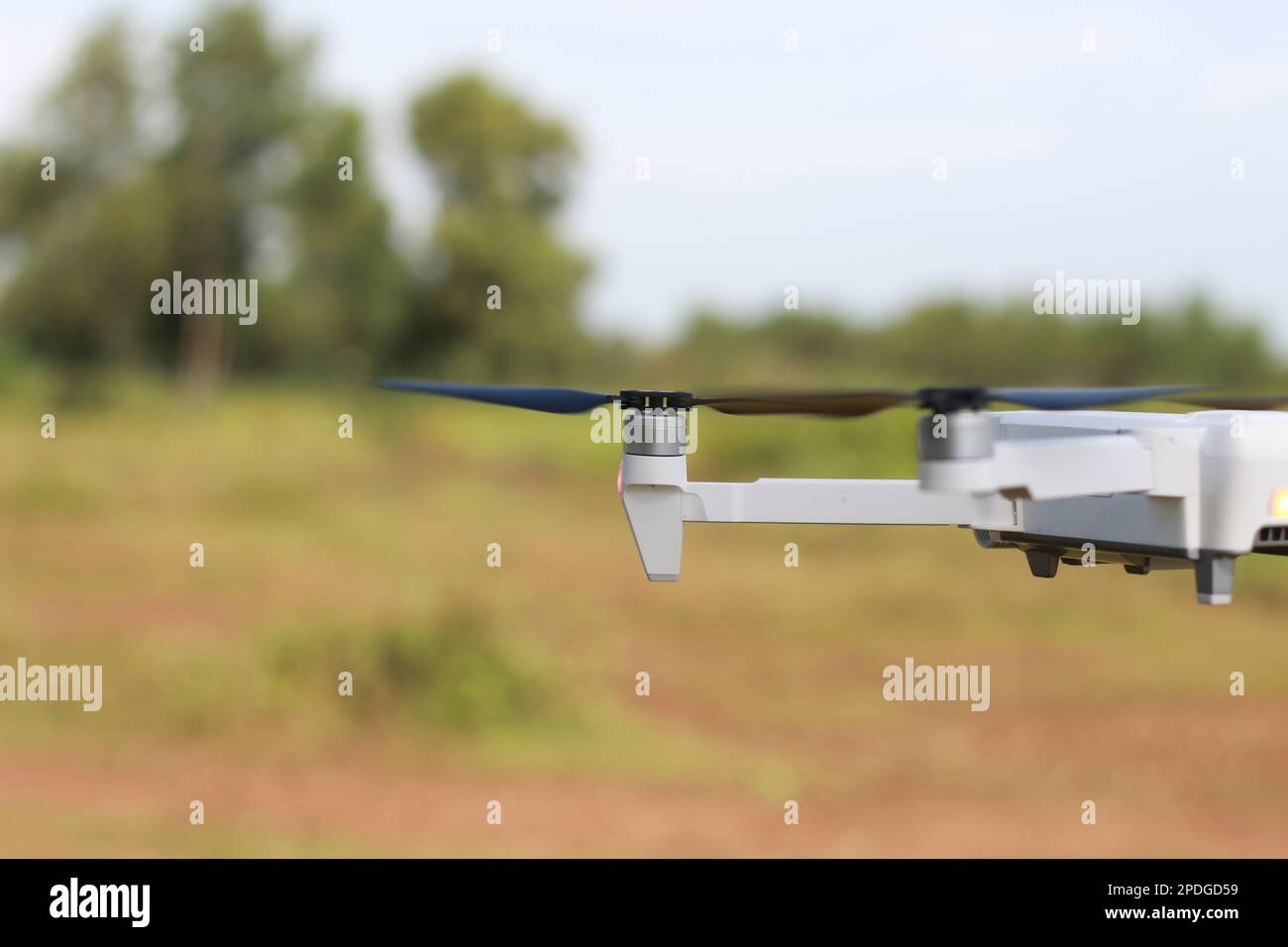 a photo of a drone flying with a blurry propeller against a green open ...