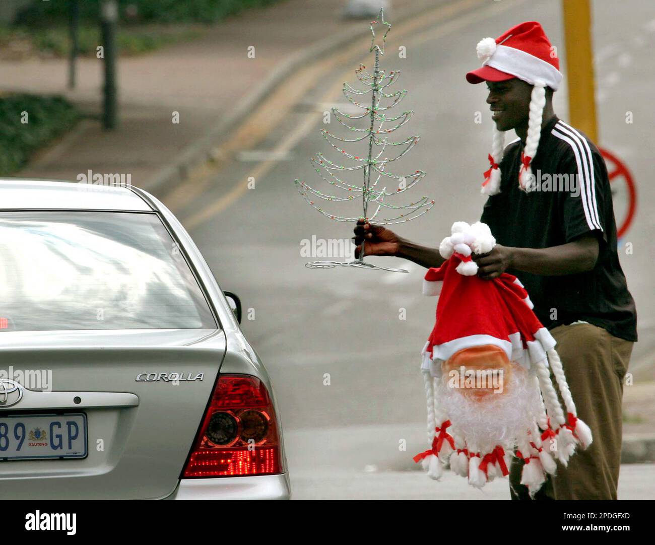 A street hawker sells Santa Claus masks and a wire Christmas trees at a ...