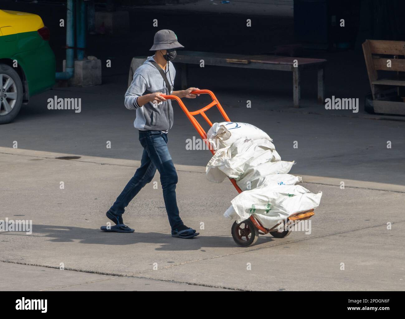 A man pushes a cart loaded with sacks, Thailand Stock Photo - Alamy