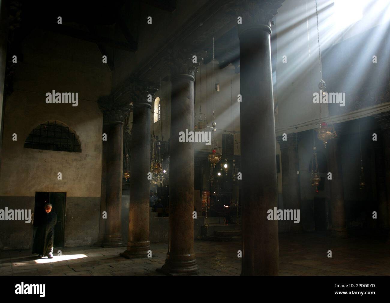 Rays of light are seen from a window as a priest walks through the ...