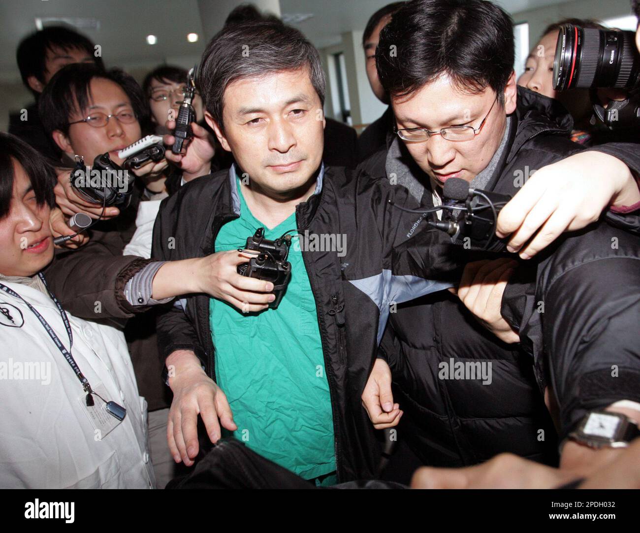 South Korean stem cell pioneer Hwang Woo-Suk, center, leaves his office ...