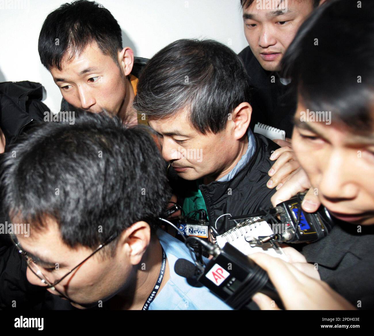 South Korean stem cell pioneer Hwang Woo-Suk, center, leaves his office ...