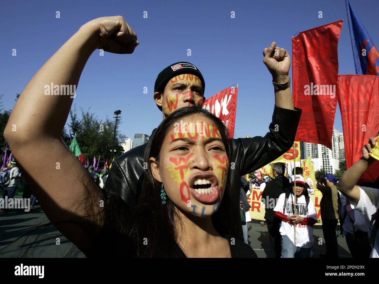 With anti-WTO signs printed on their faces, protesters shout slogans as ...