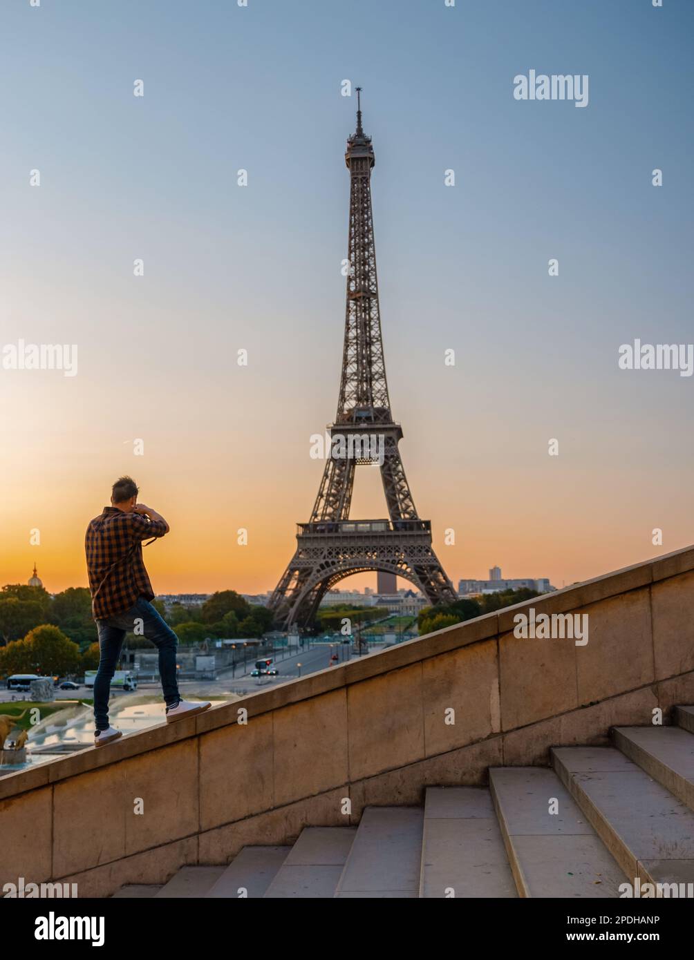 Young men photographing the Eiffel tower at Sunrise, a man took a photo ...